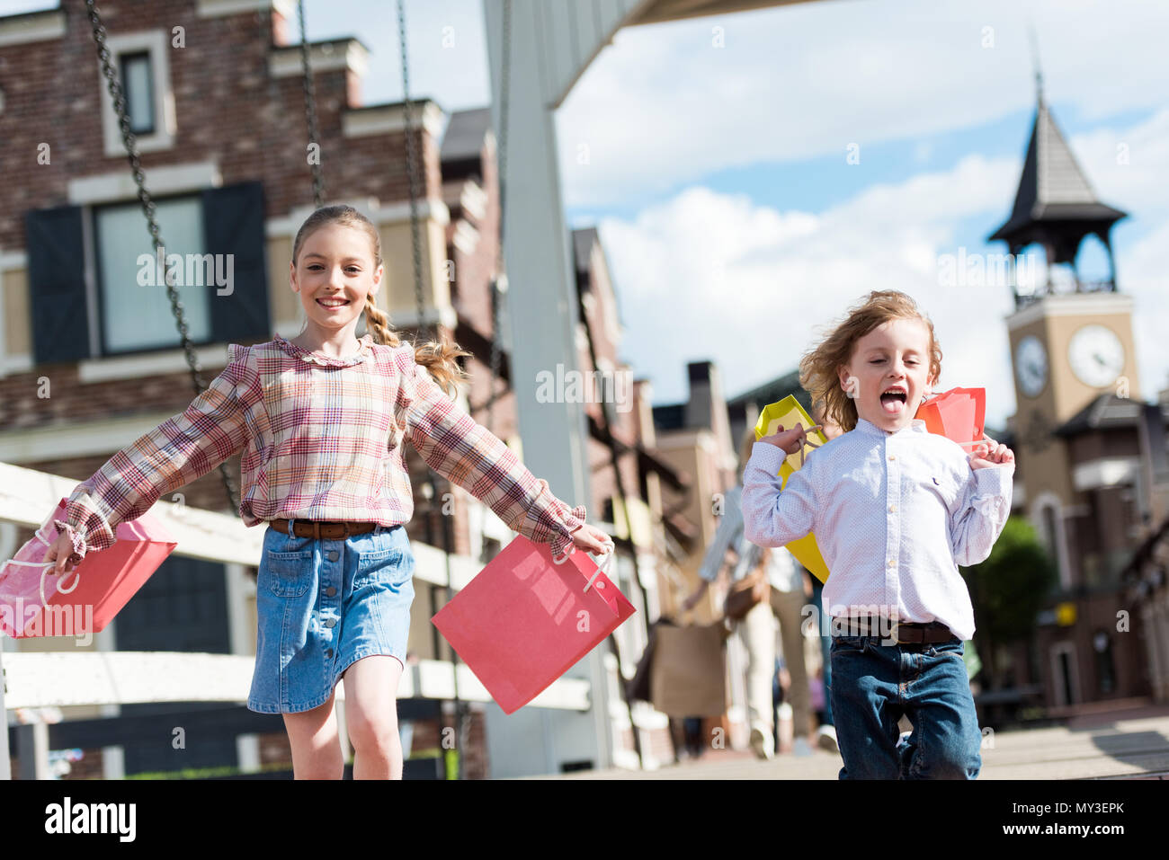 Adorable happy children holding shopping bags and running together at ...