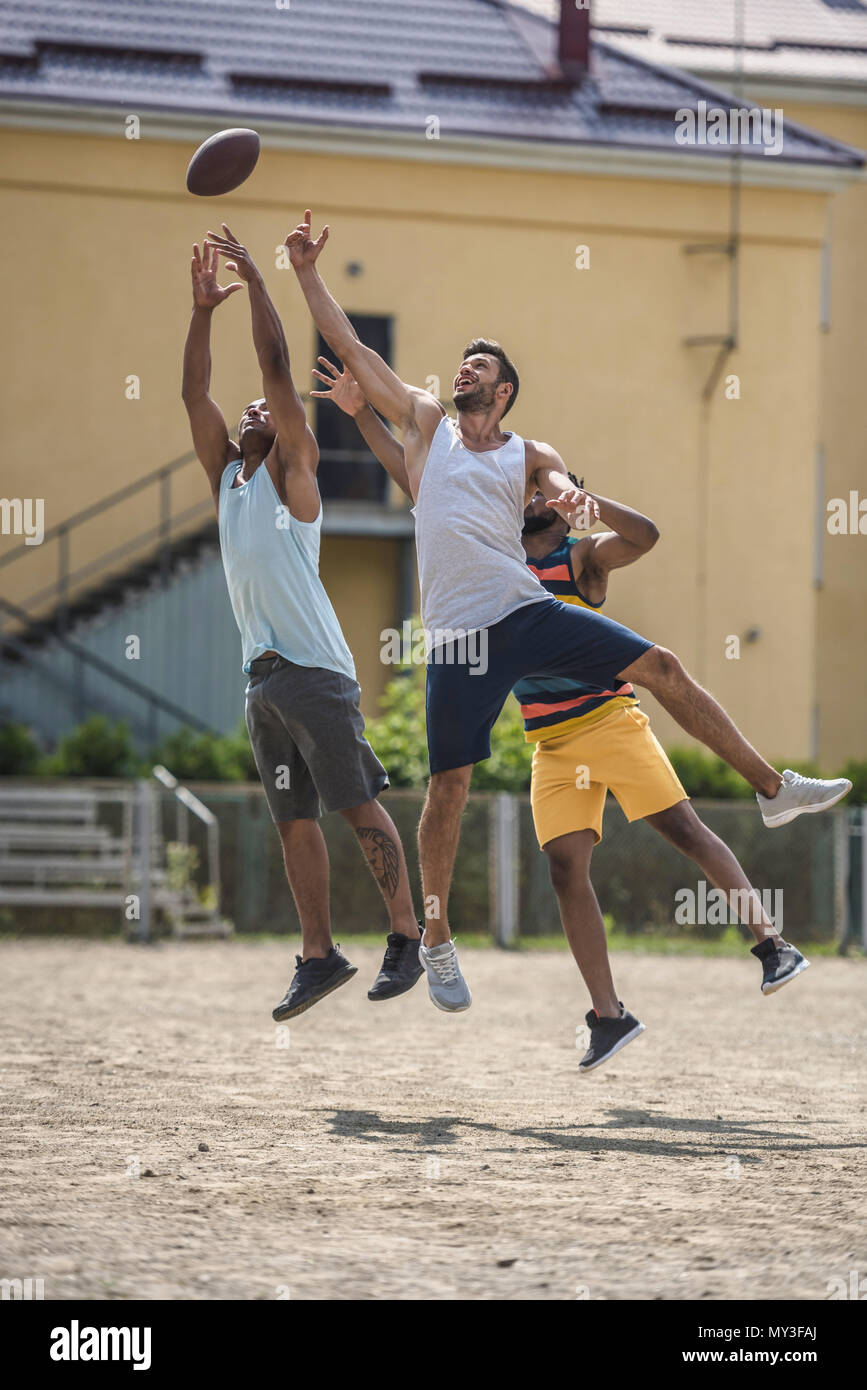 group of young multicultural men playing football on court Stock Photo ...