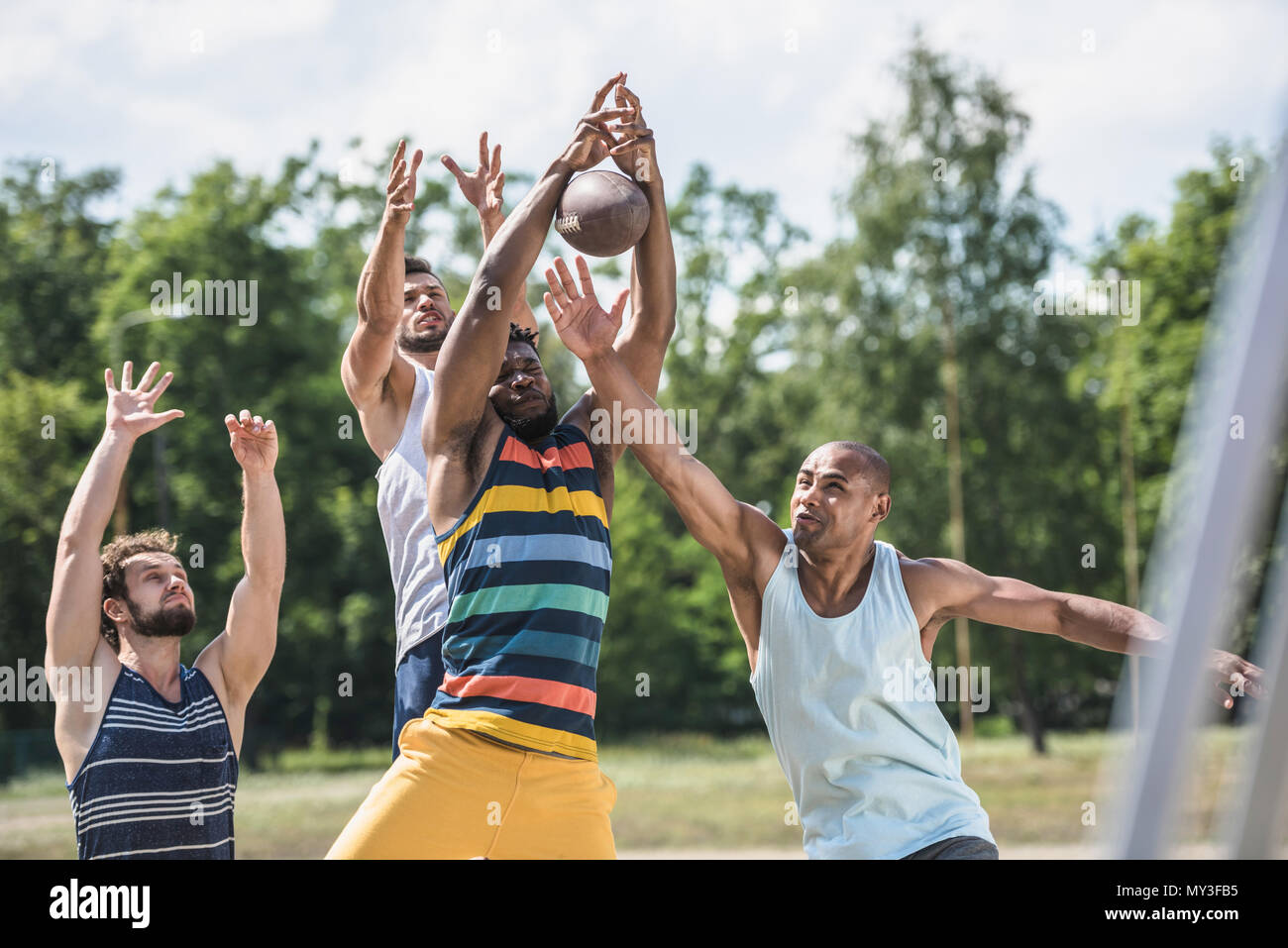 group of young multicultural men playing football on court Stock Photo ...