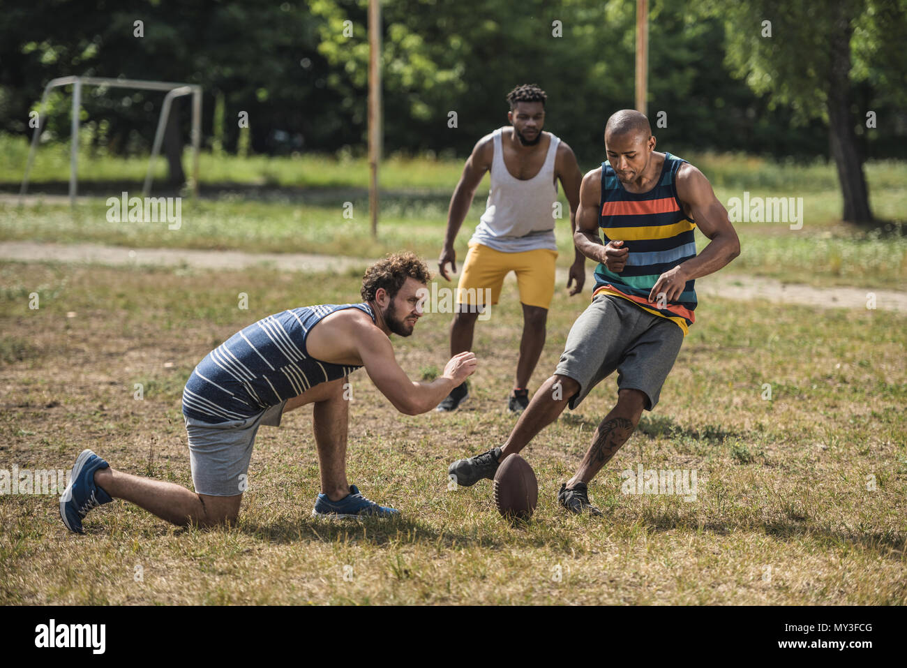 group of young multicultural men playing football on court Stock Photo ...