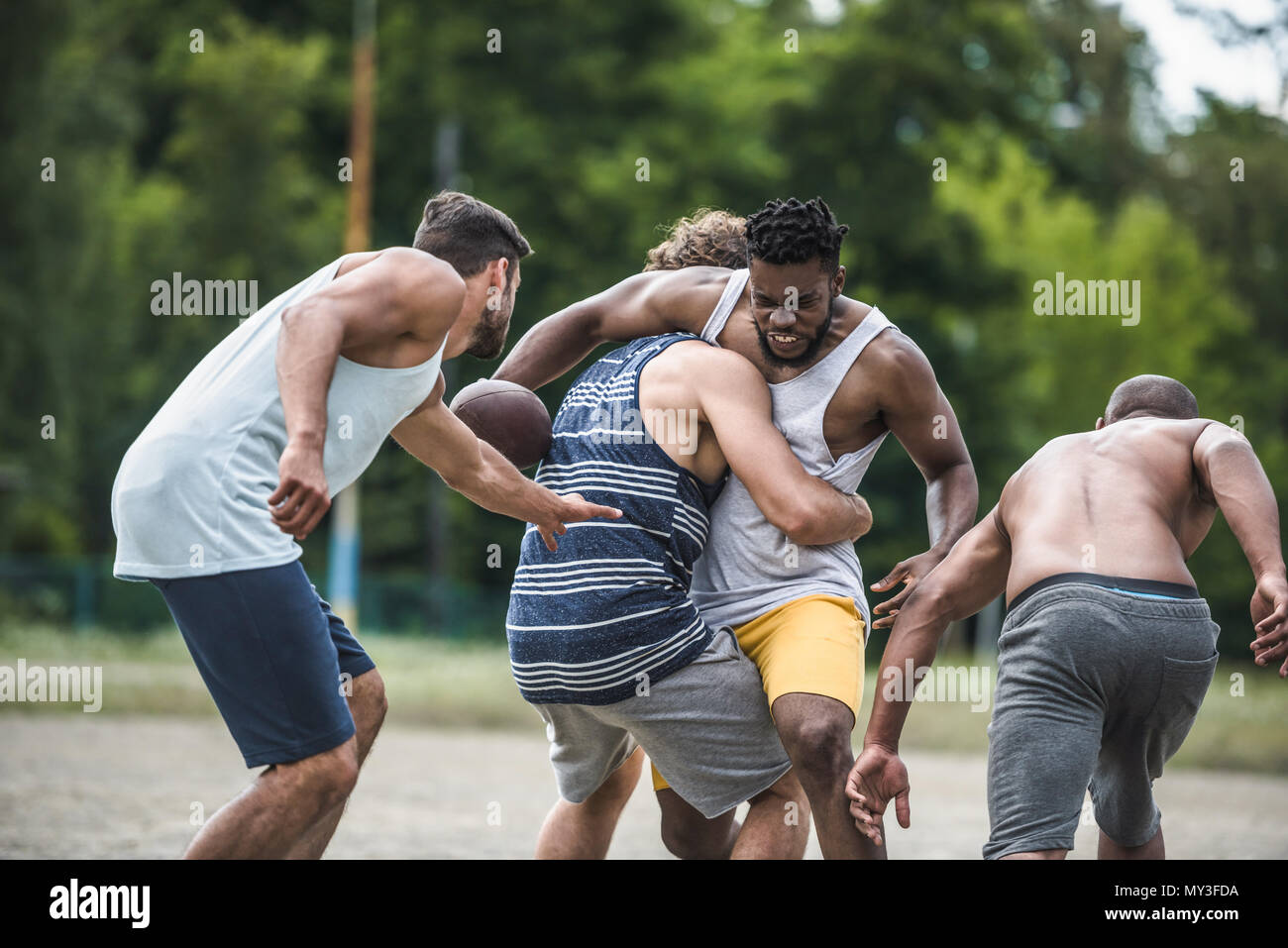 group of young multicultural men playing football on court Stock Photo ...