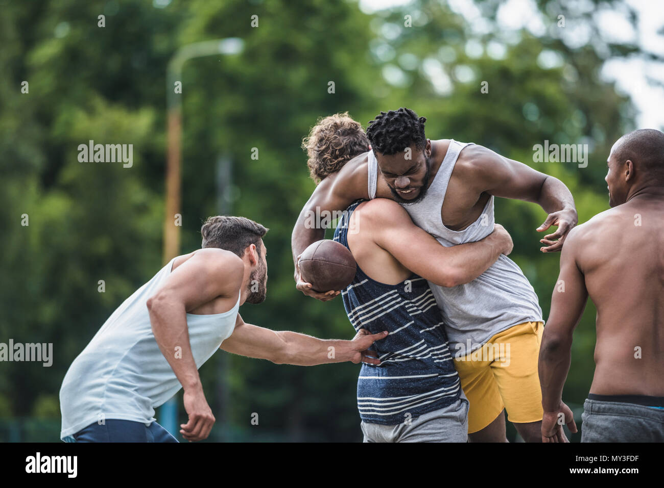 group of young multicultural men playing football on court Stock Photo ...