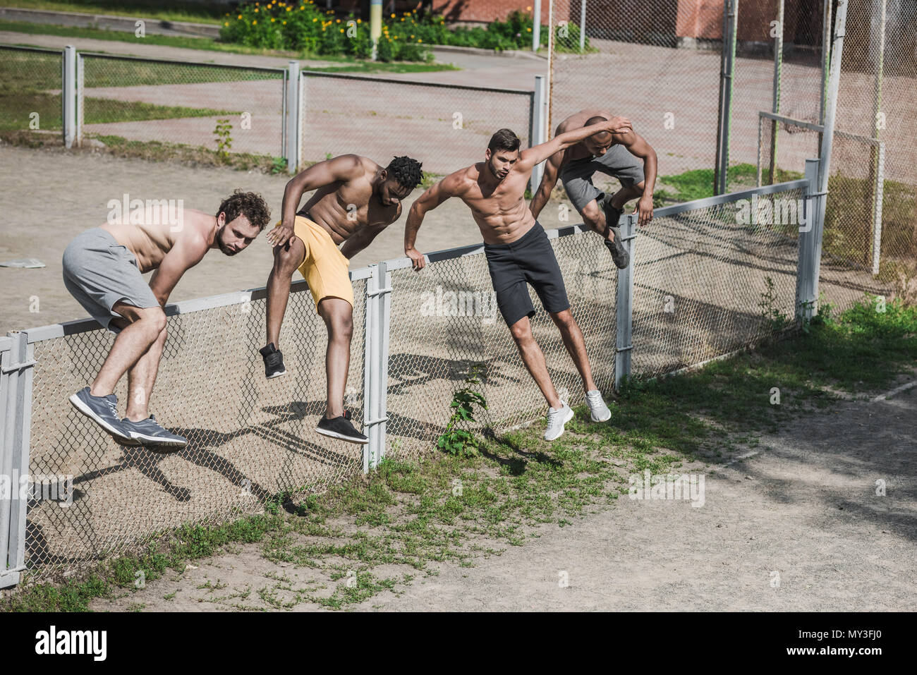Group of young handsome men jumping over fence on court Stock Photo - Alamy