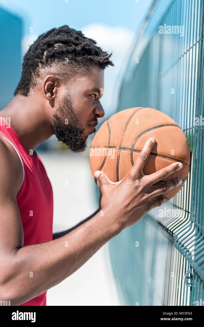 side view of african american basketball player holding ball in hands ...