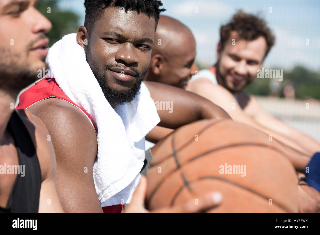 side view of multicultural basketball team resting after game on court ...