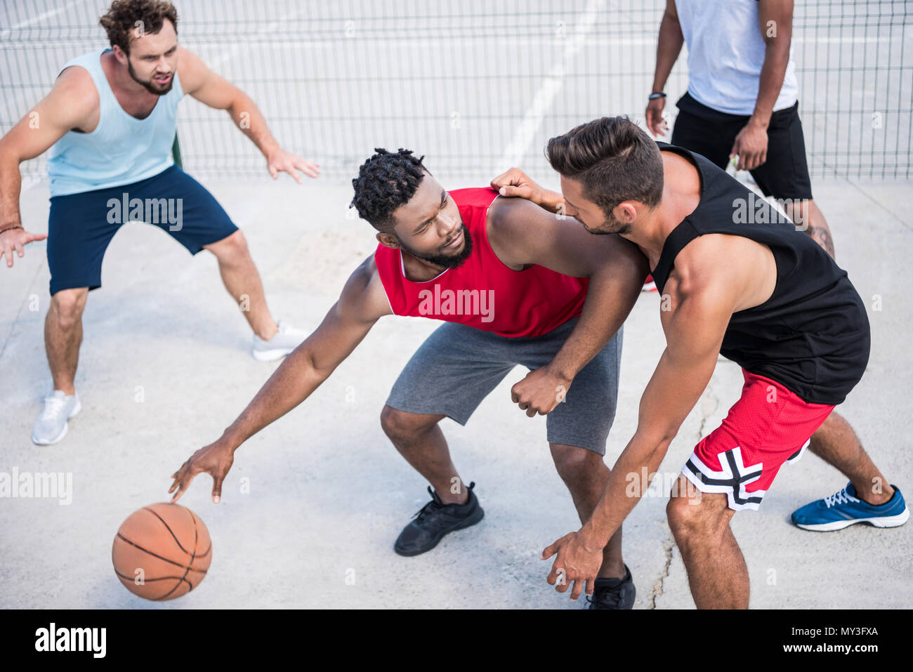 group of young multicultural men playing basketball on court Stock ...