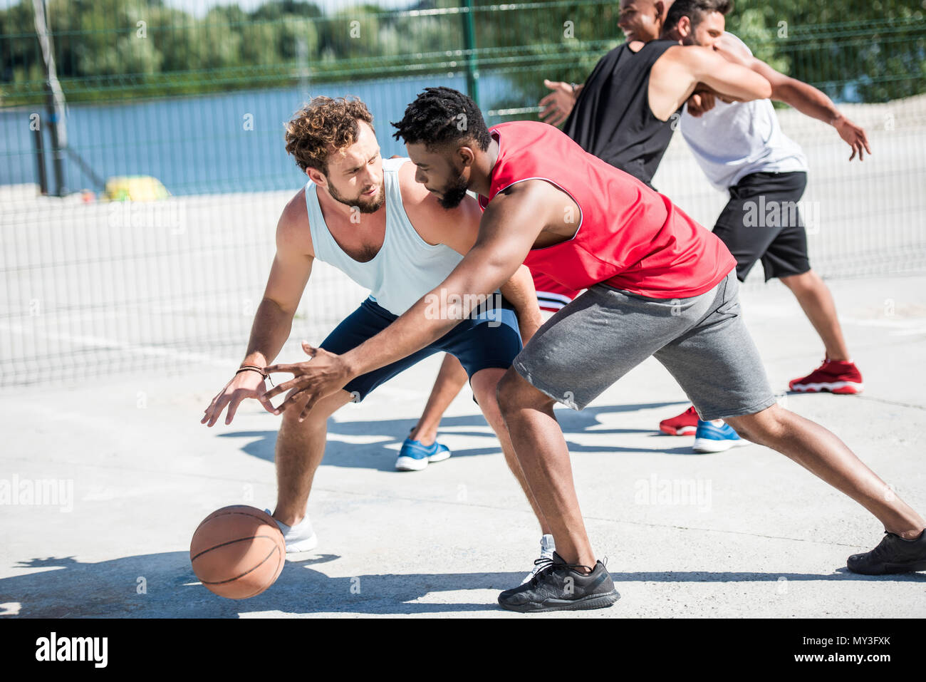 group of young multicultural men playing basketball on court Stock ...