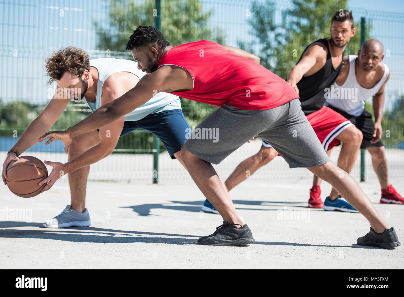 group of young multicultural men playing basketball on court Stock ...
