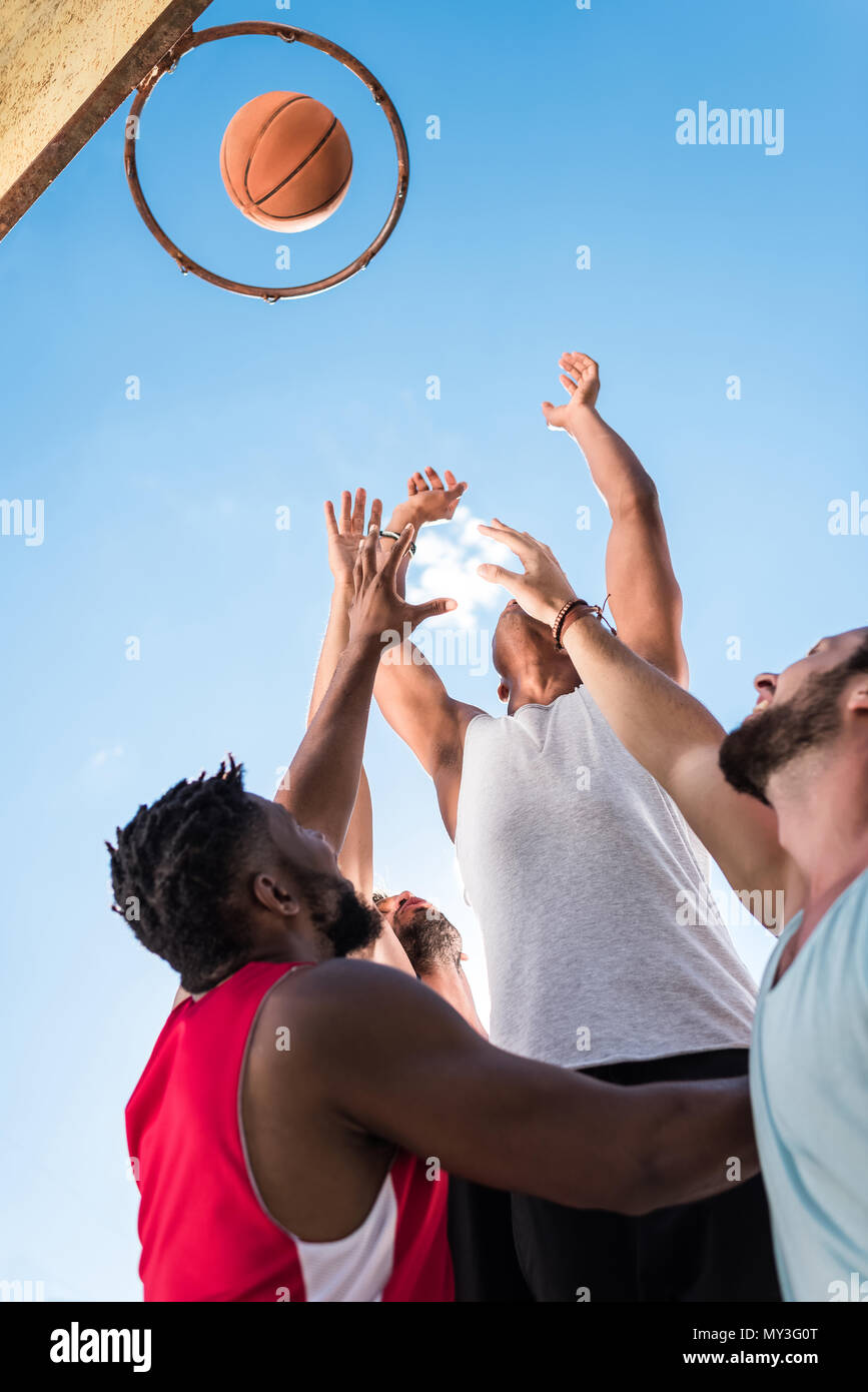 low angle view of multicultural basketball players struggling to catch ...