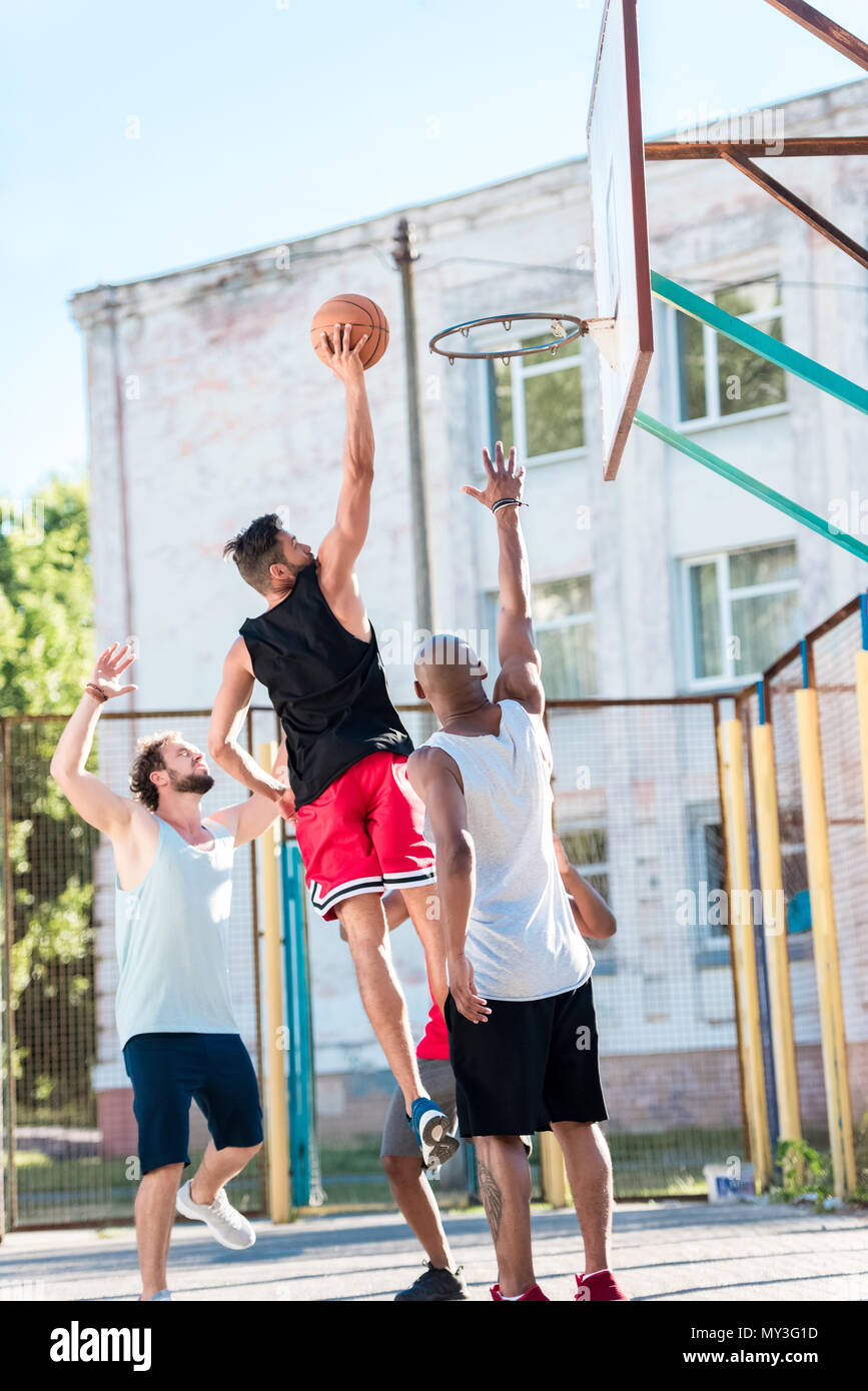 multicultural basketball team playing basketball together on court ...