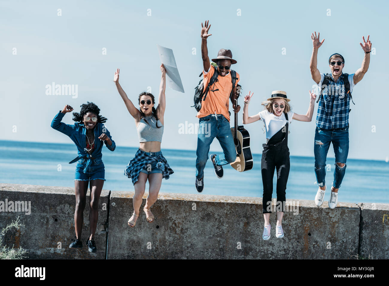 multicultural group of young friends jumping of parapet together Stock ...