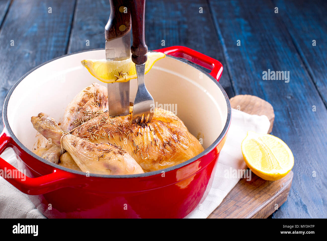 a cast-iron pot and a golden chicken with lemon and rosemary from the ...
