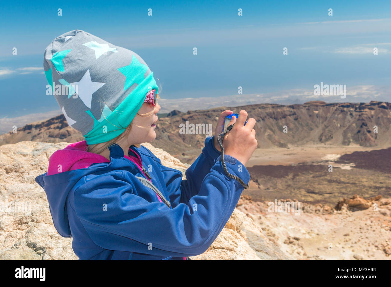 Girl with cap photographs a mountainous landscape in sunshine, portrait ...