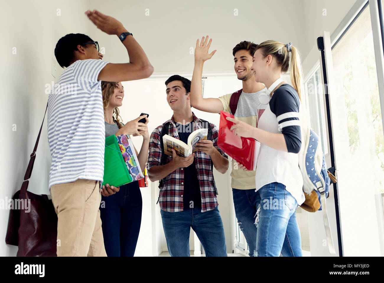 Students giving each other a high-five in corridor Stock Photo - Alamy