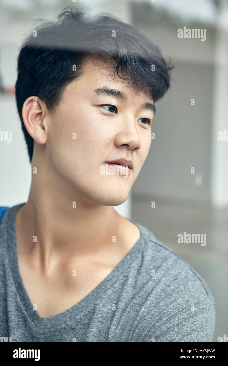 Young man looking through window, portrait Stock Photo - Alamy