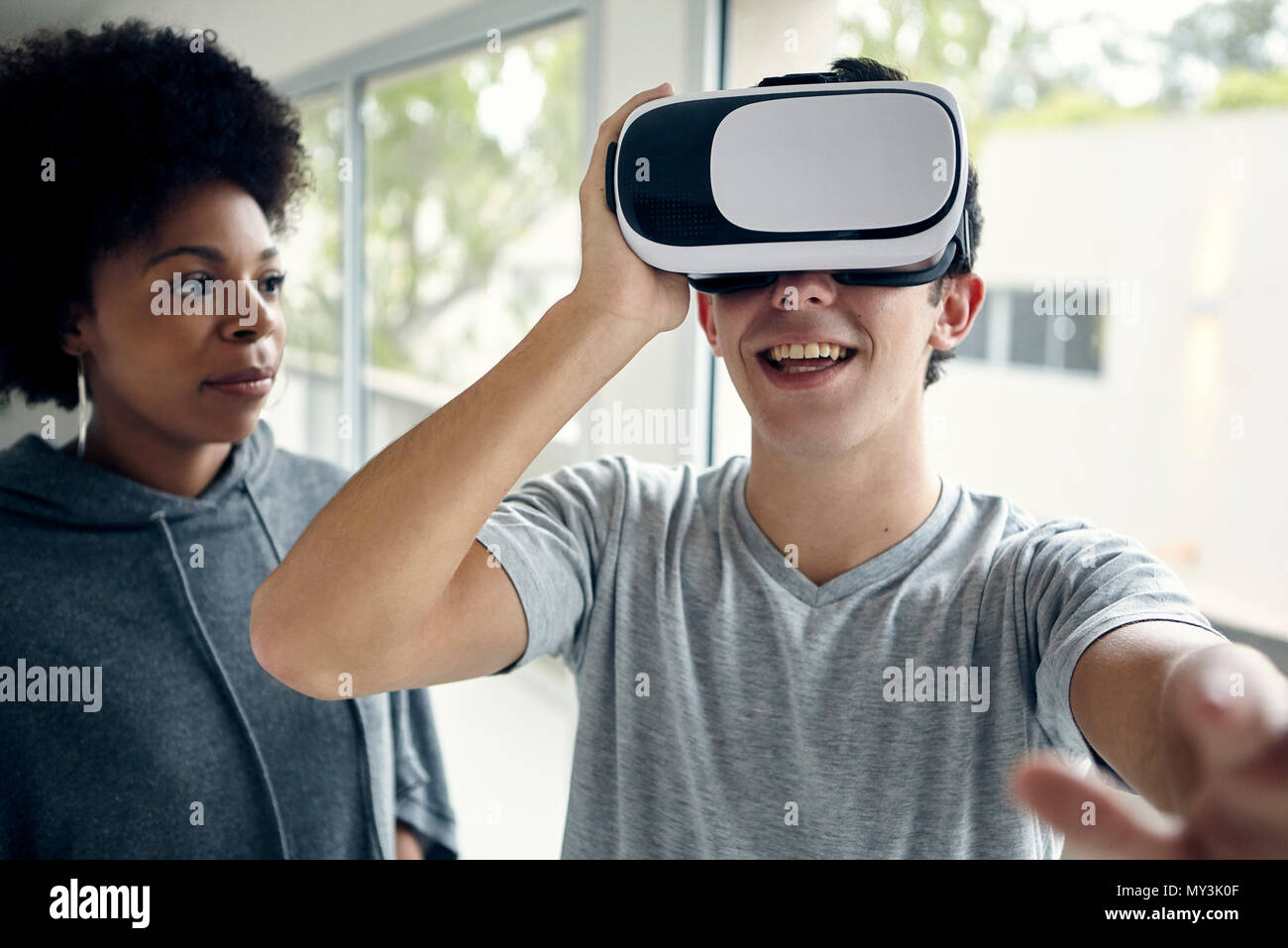 Young man using virtual reality simulator with friend Stock Photo - Alamy