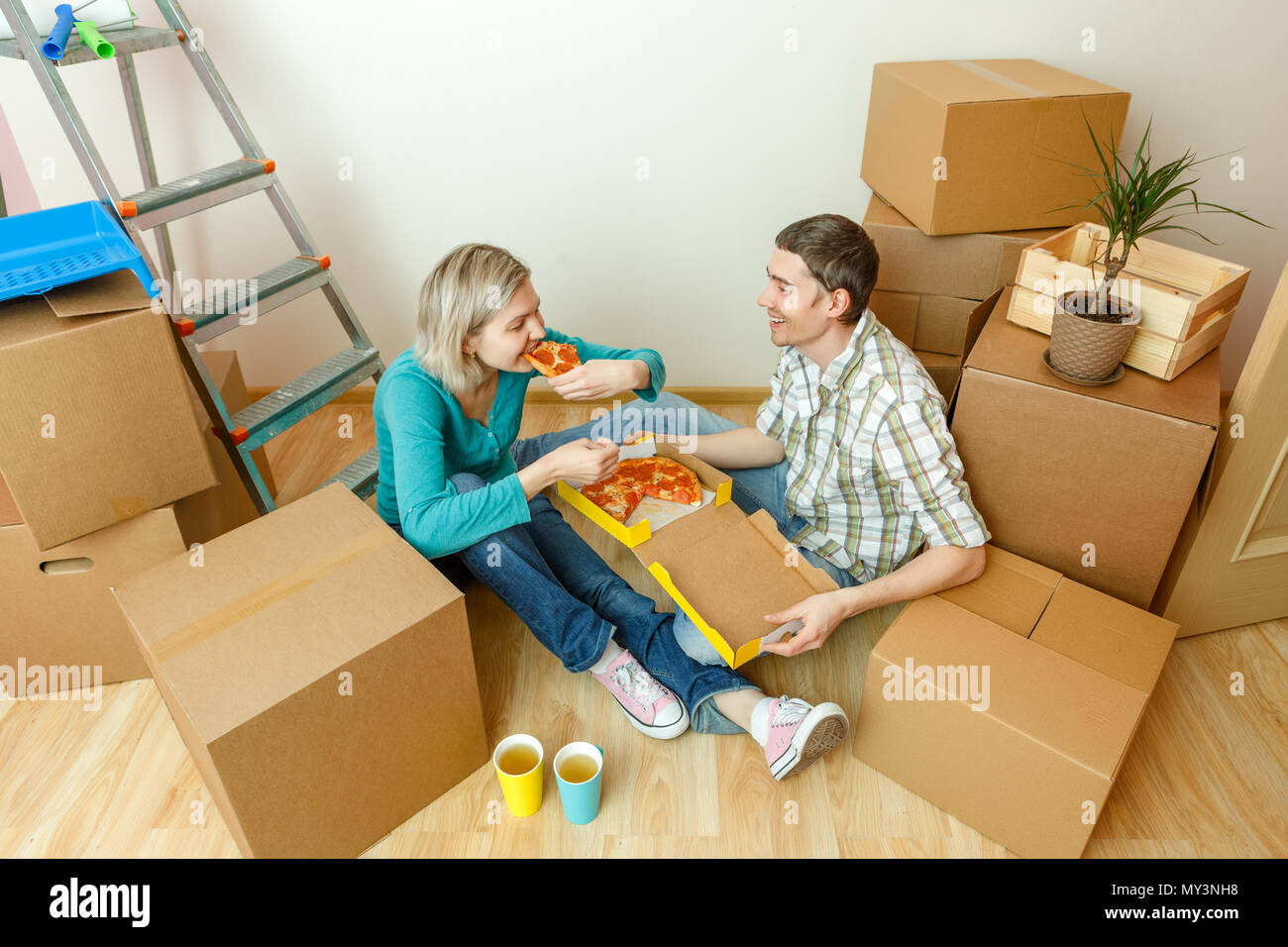 Photos of women and men eating pizza among cardboard boxes Stock Photo ...