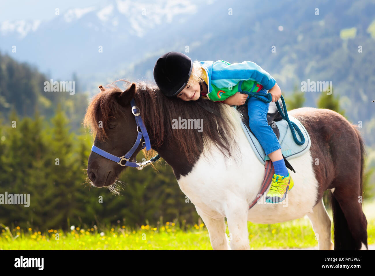 Kids riding pony in the Alps mountains. Family spring vacation on horse ...
