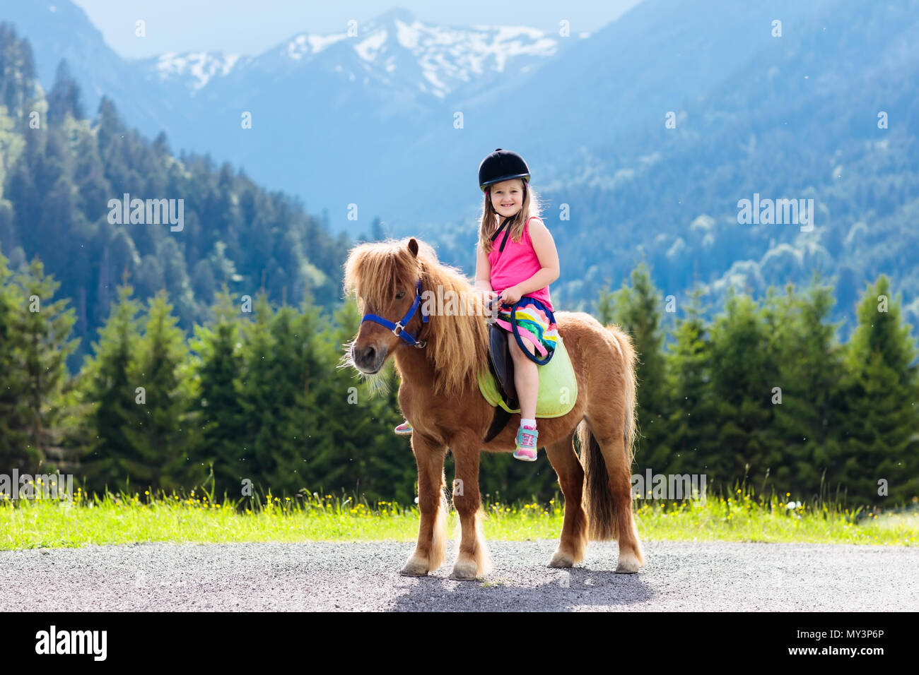 Kids riding pony in the Alps mountains. Family spring vacation on horse ...