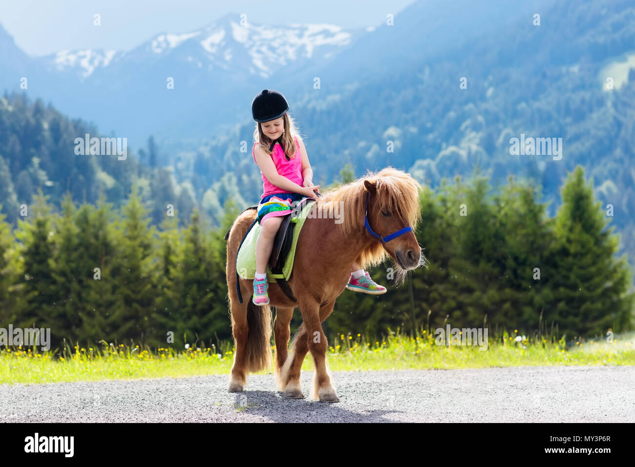 Kids riding pony in the Alps mountains. Family spring vacation on horse ...