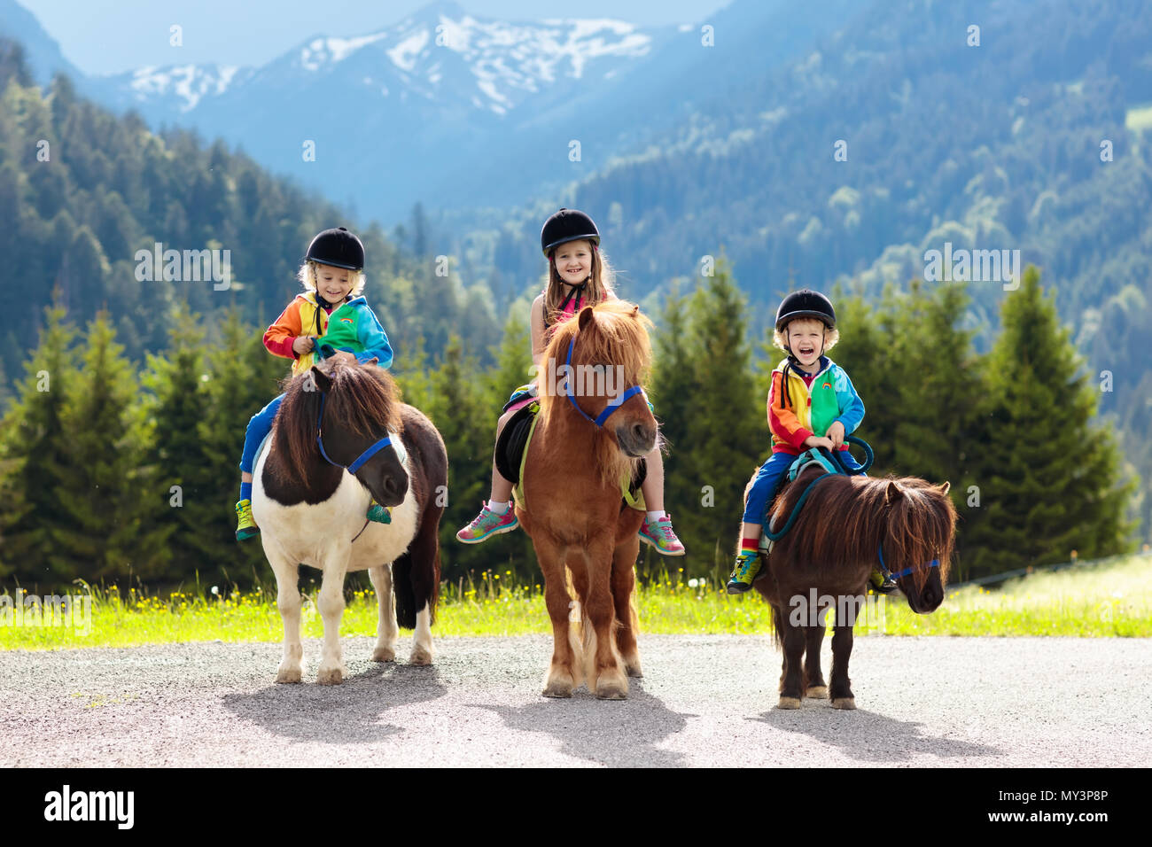Kids riding pony in the Alps mountains. Family spring vacation on horse ...