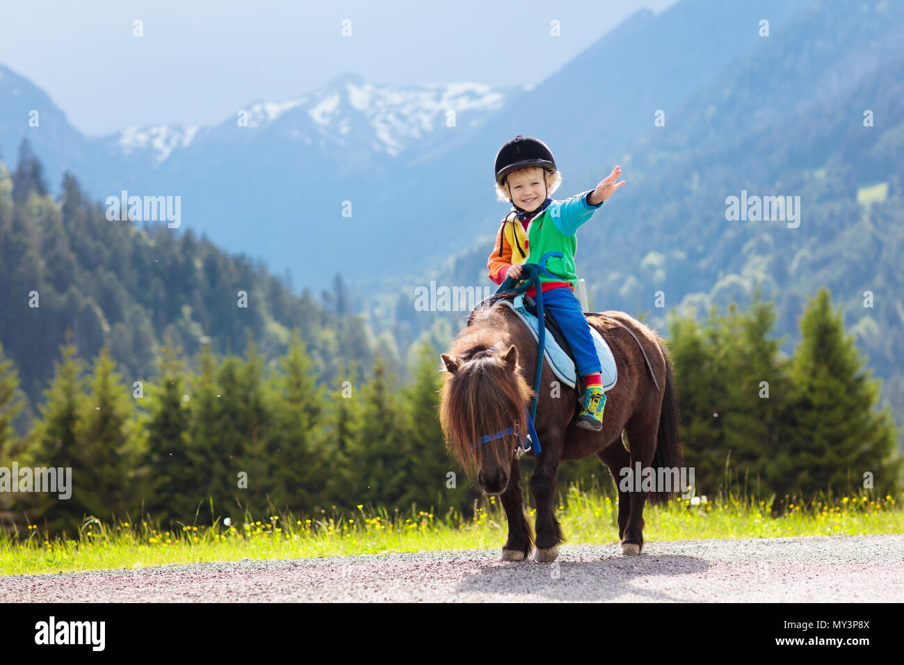 Kids riding pony in the Alps mountains. Family spring vacation on horse ...