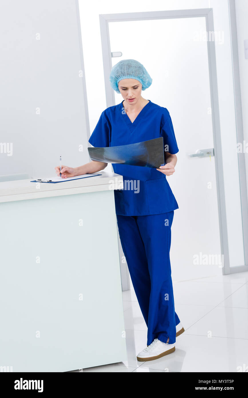 female surgeon looking at x-ray and writing diagnosis in clinic Stock ...
