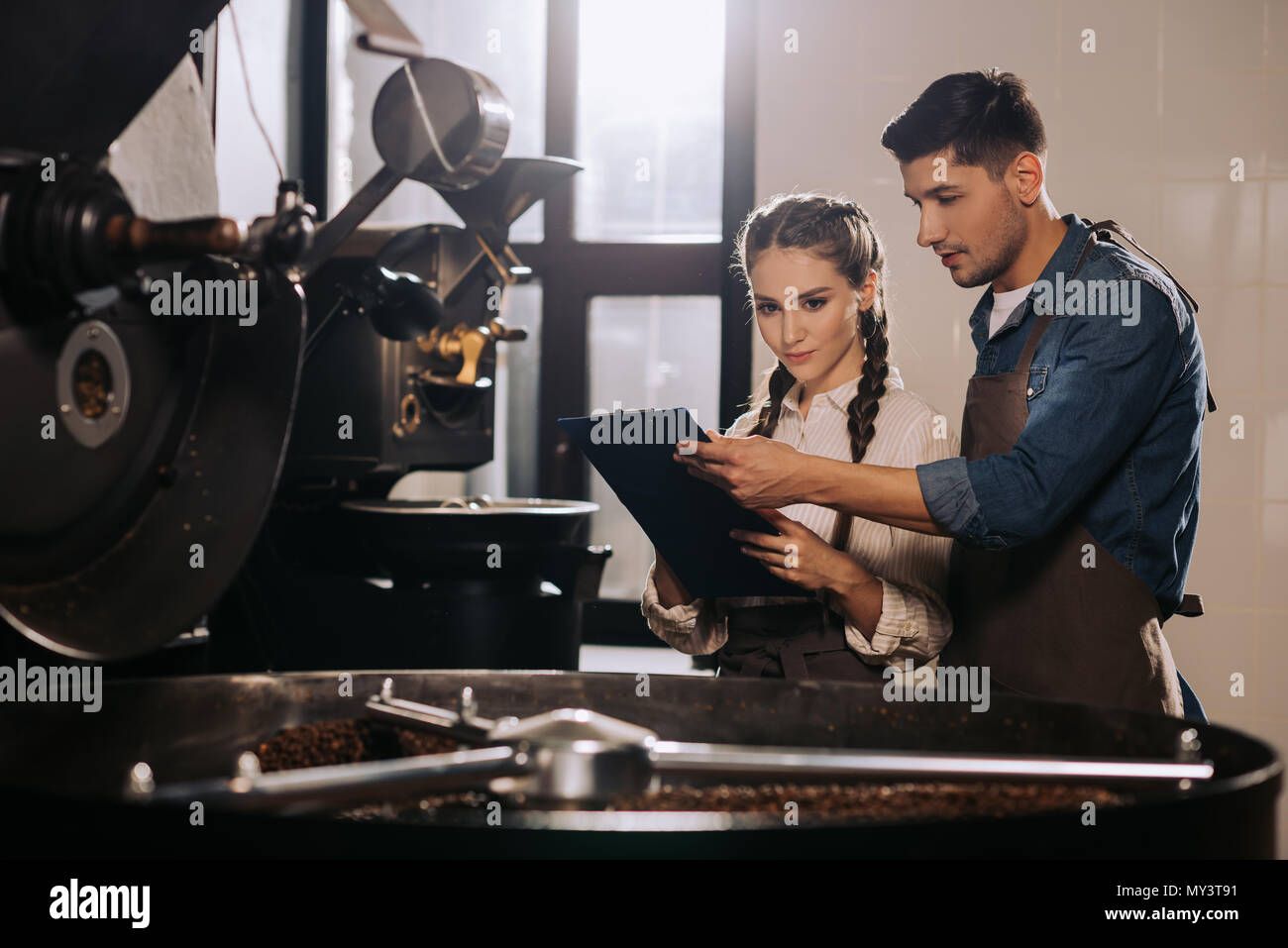 coffee shop workers checking coffee beans roasting process together ...