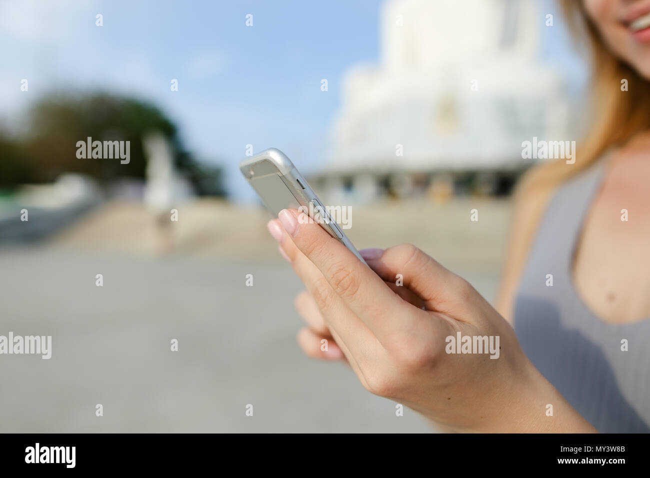 Close up beautiful girl talking by smartphone near Buddha white statue ...