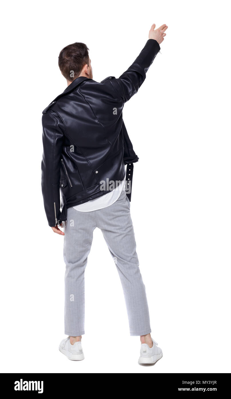 Back view of a stylish man in a leather jacket points his hand upwards ...
