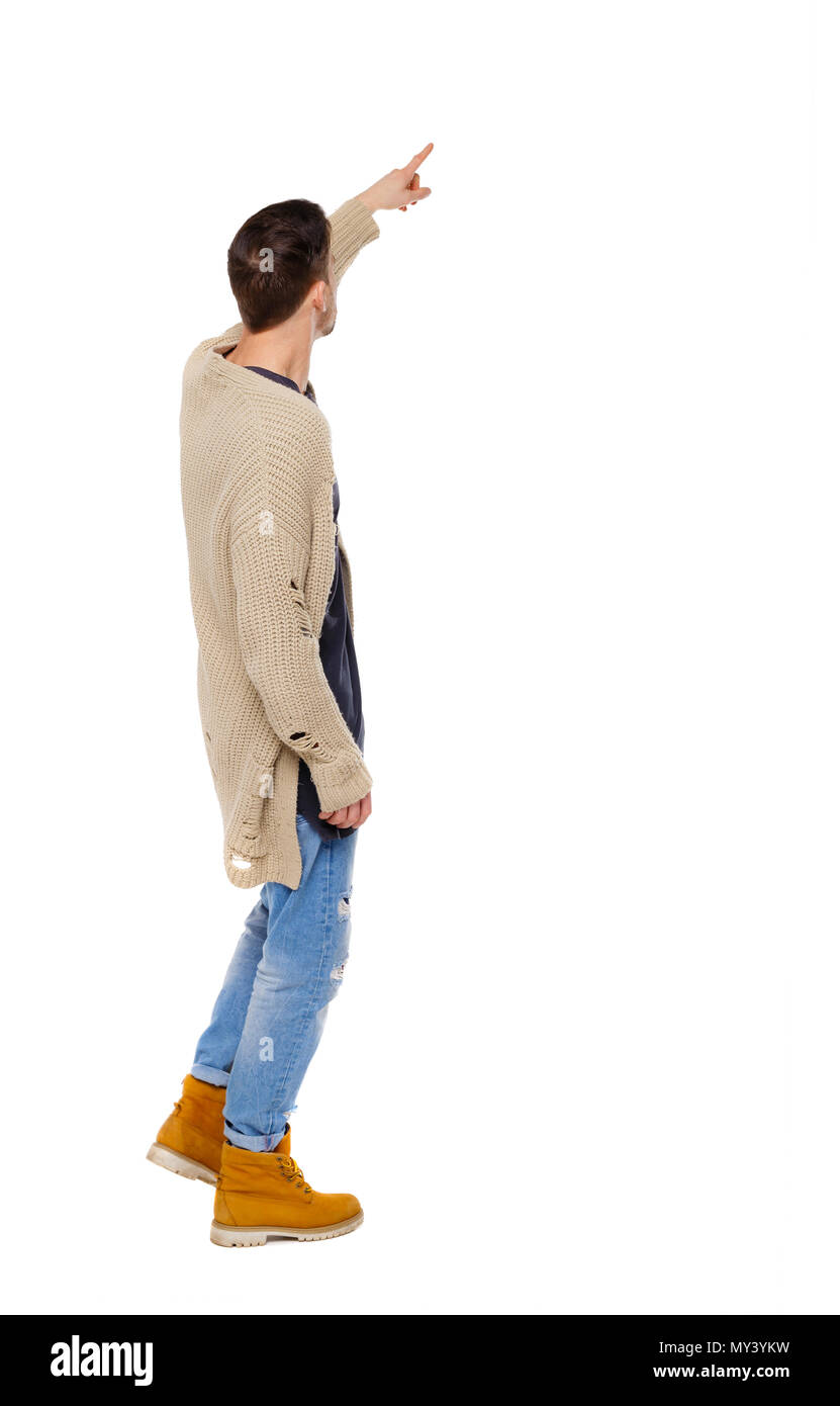 Back view of a stylish man in a knitted sweater points his hand upwards ...