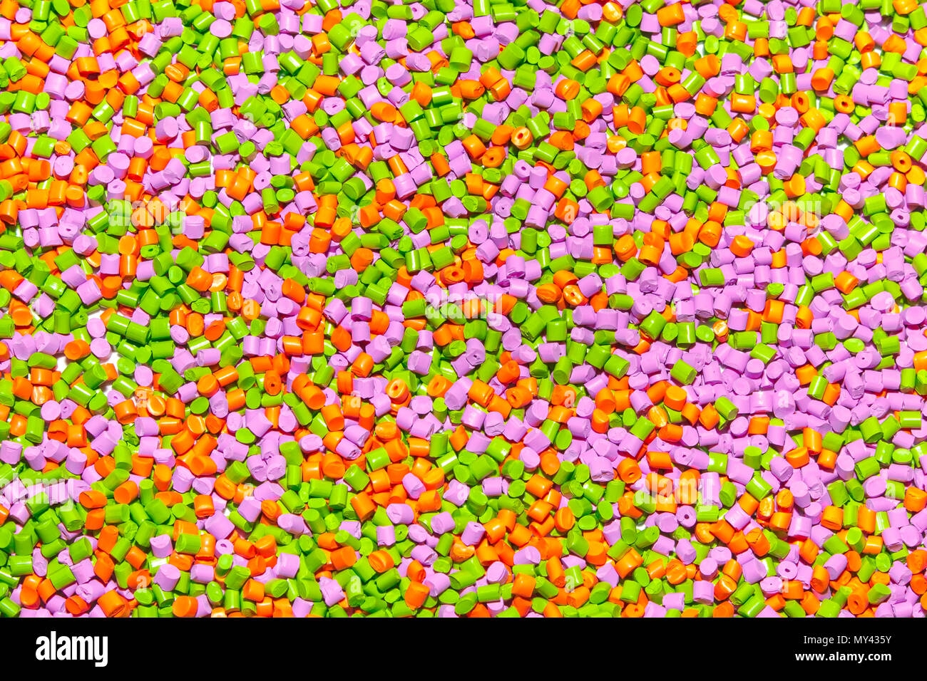 Plastic pellets. Orange green and pink Polypropylene granules scattered ...