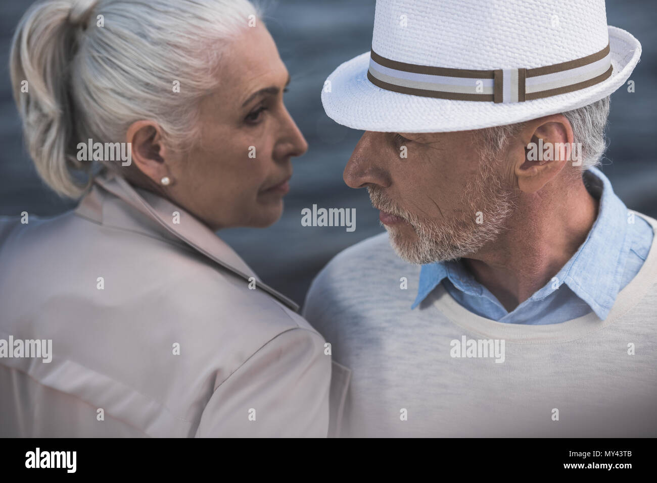 portrait of casual grey haired couple able to kiss while standing ...