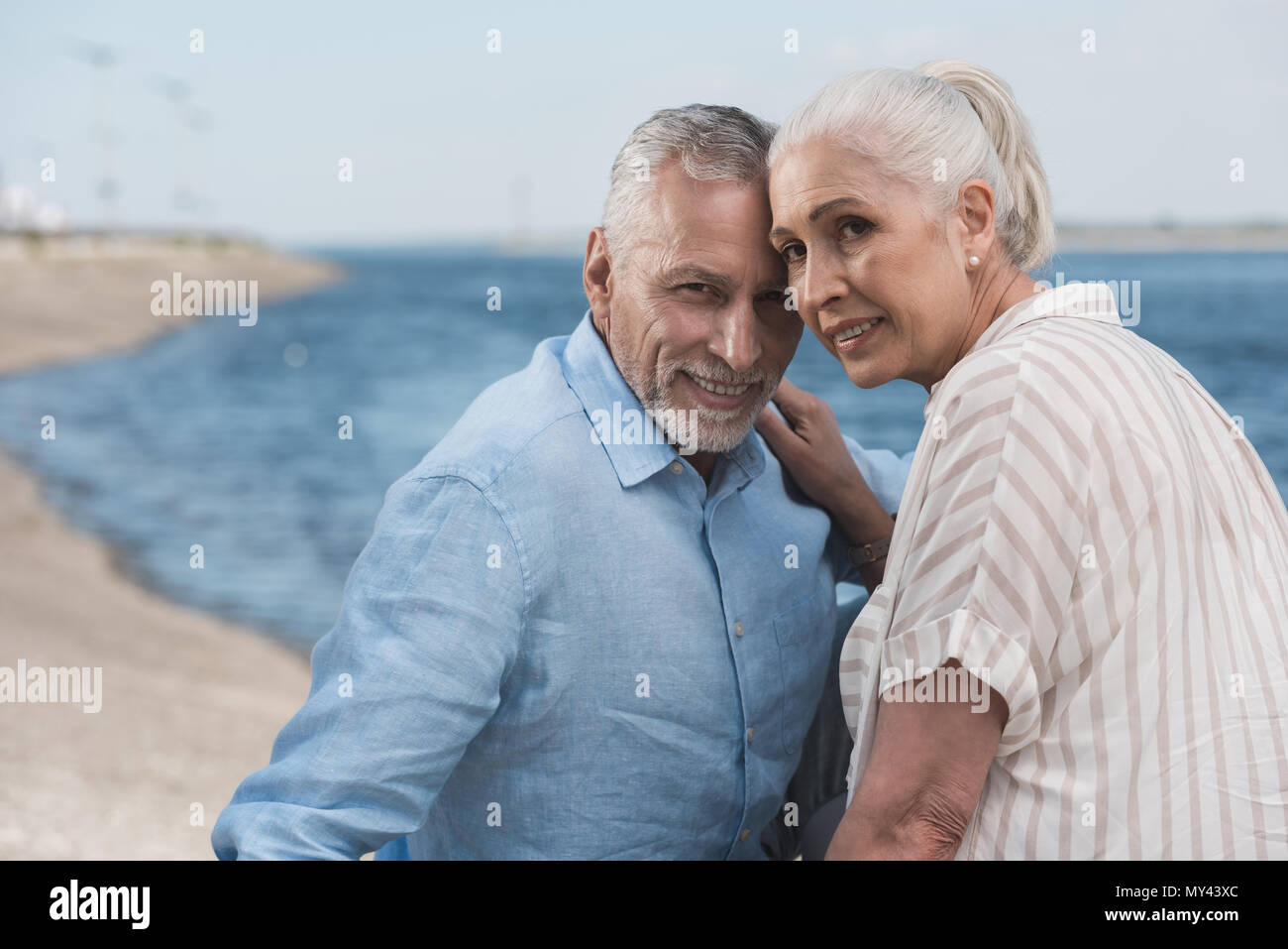 casual grey haired couple smiling and embracing at quay Stock Photo - Alamy