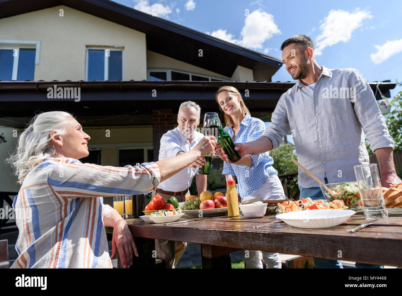 happy family of two generations clinking glasses and bottles with ...
