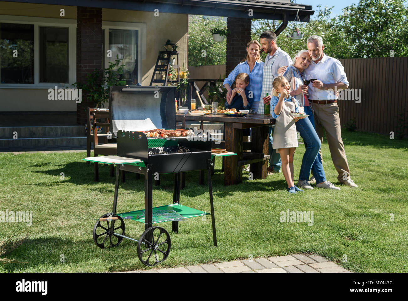 family spend time together while having barbecue with grill at yard ...