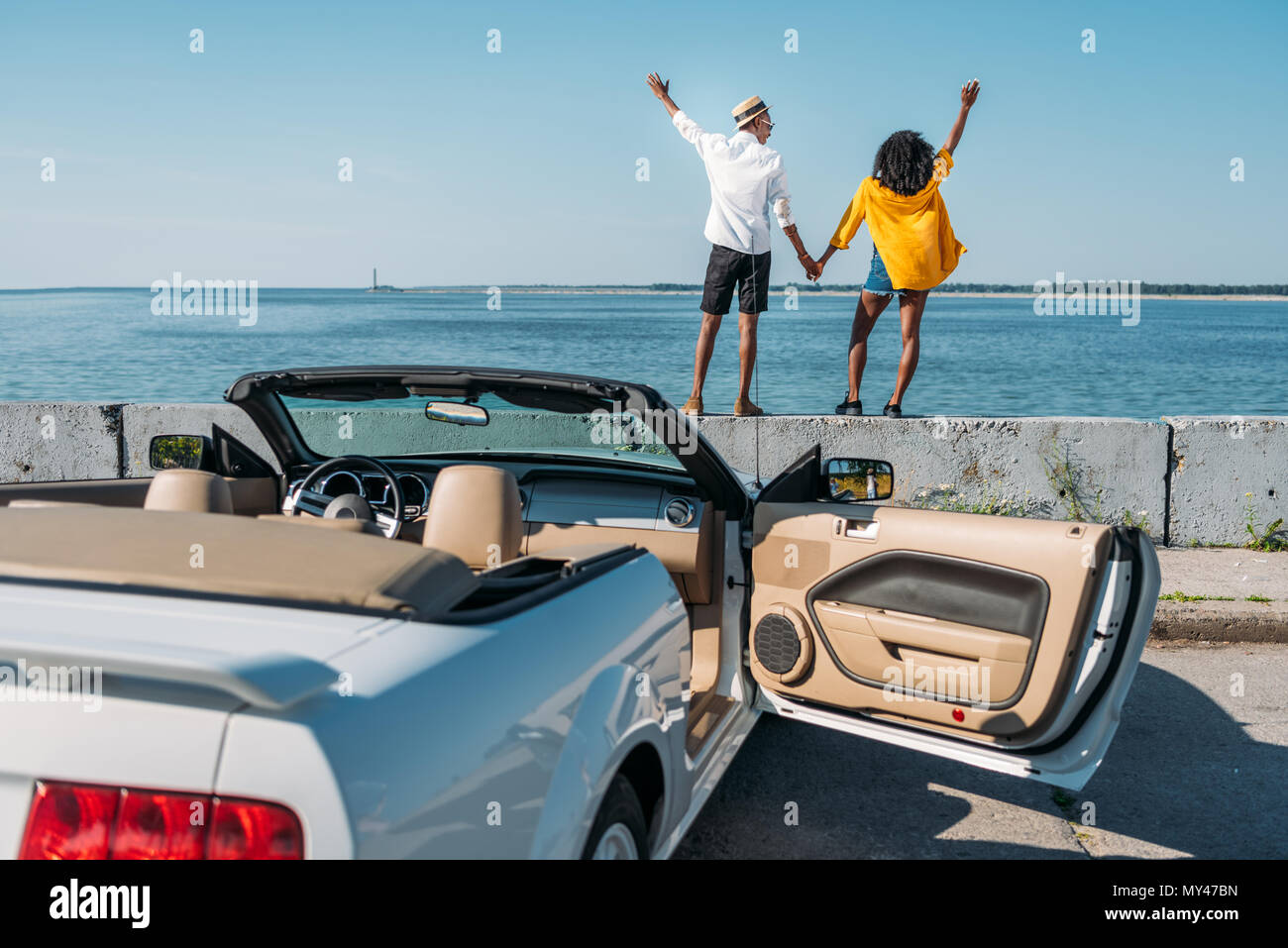 african american couple holding hands while standing on parapet at seaside Stock Photo - Alamy