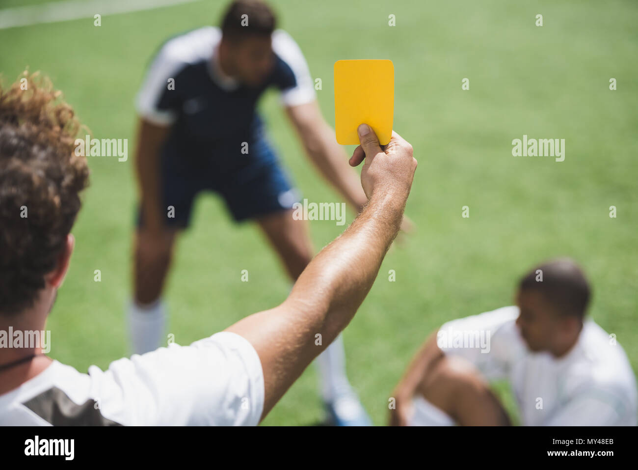 back view of soccer referee showing yellow card to players during game ...