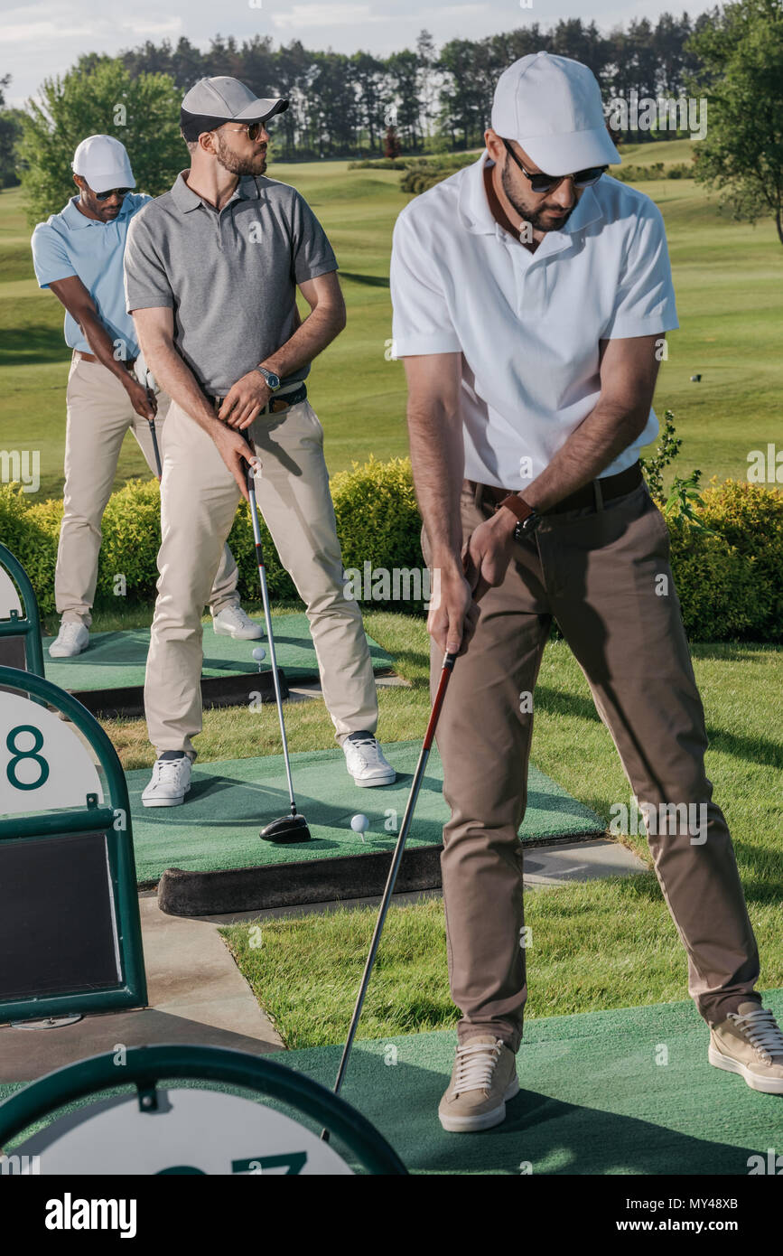 group of focused men playing golf together at golf course Stock Photo ...