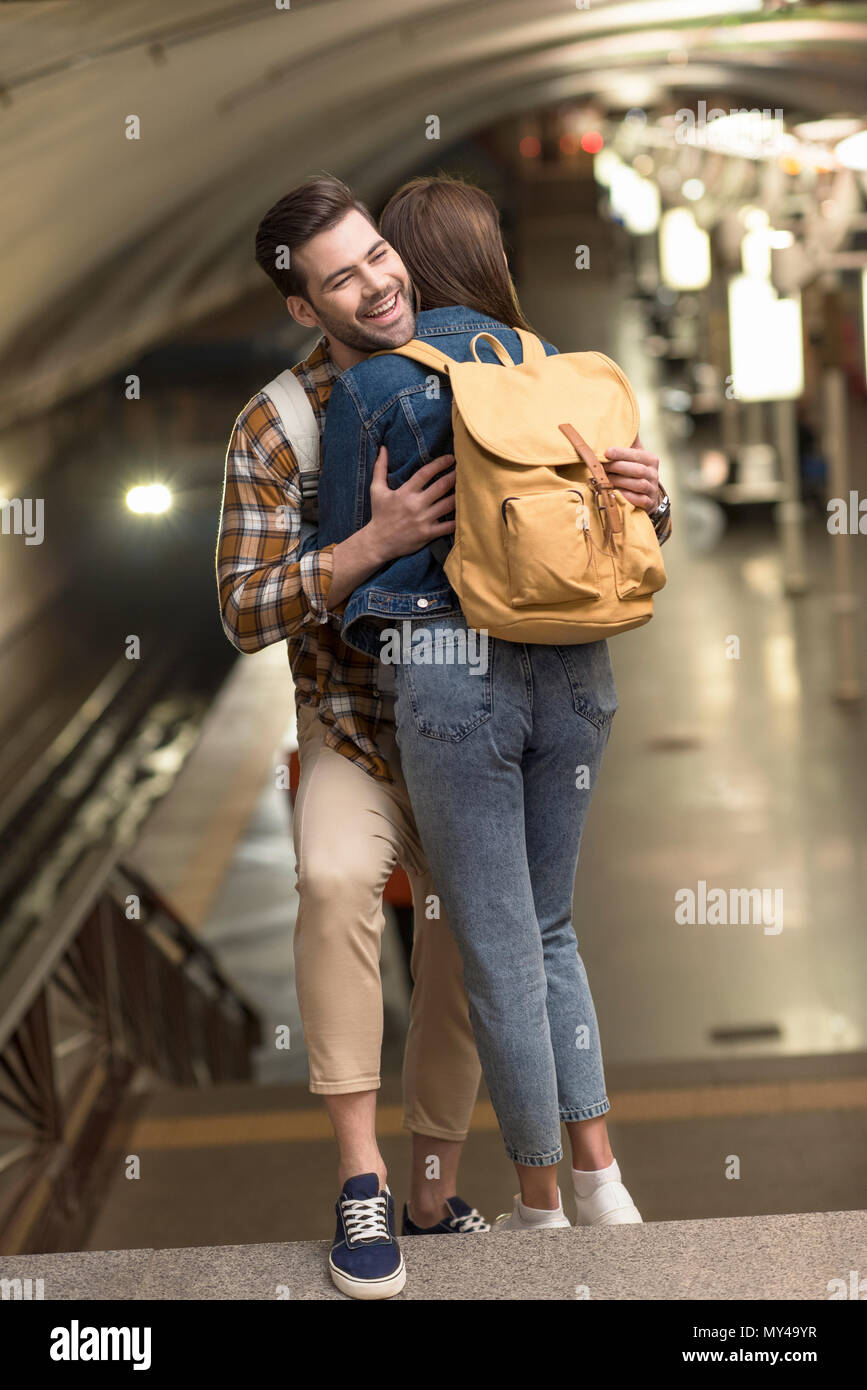 stylish male tourist with backpack hugging girlfriend at subway station ...