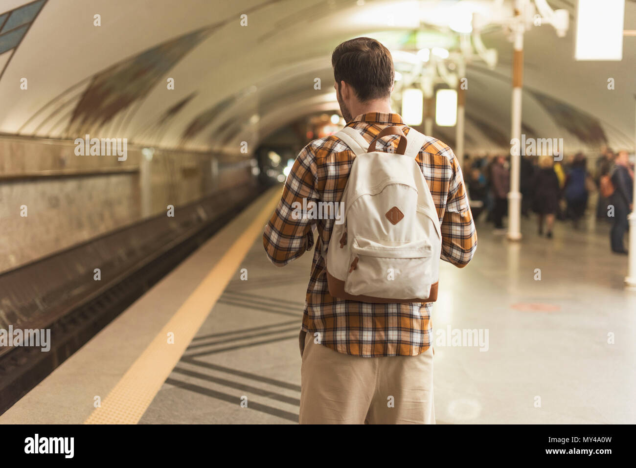 rear view of stylish man with backpack at subway station Stock Photo ...