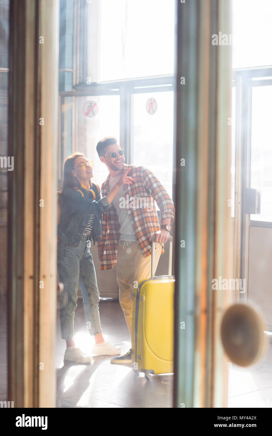 female traveler pointing by finger to boyfriend with wheeled bag at ...