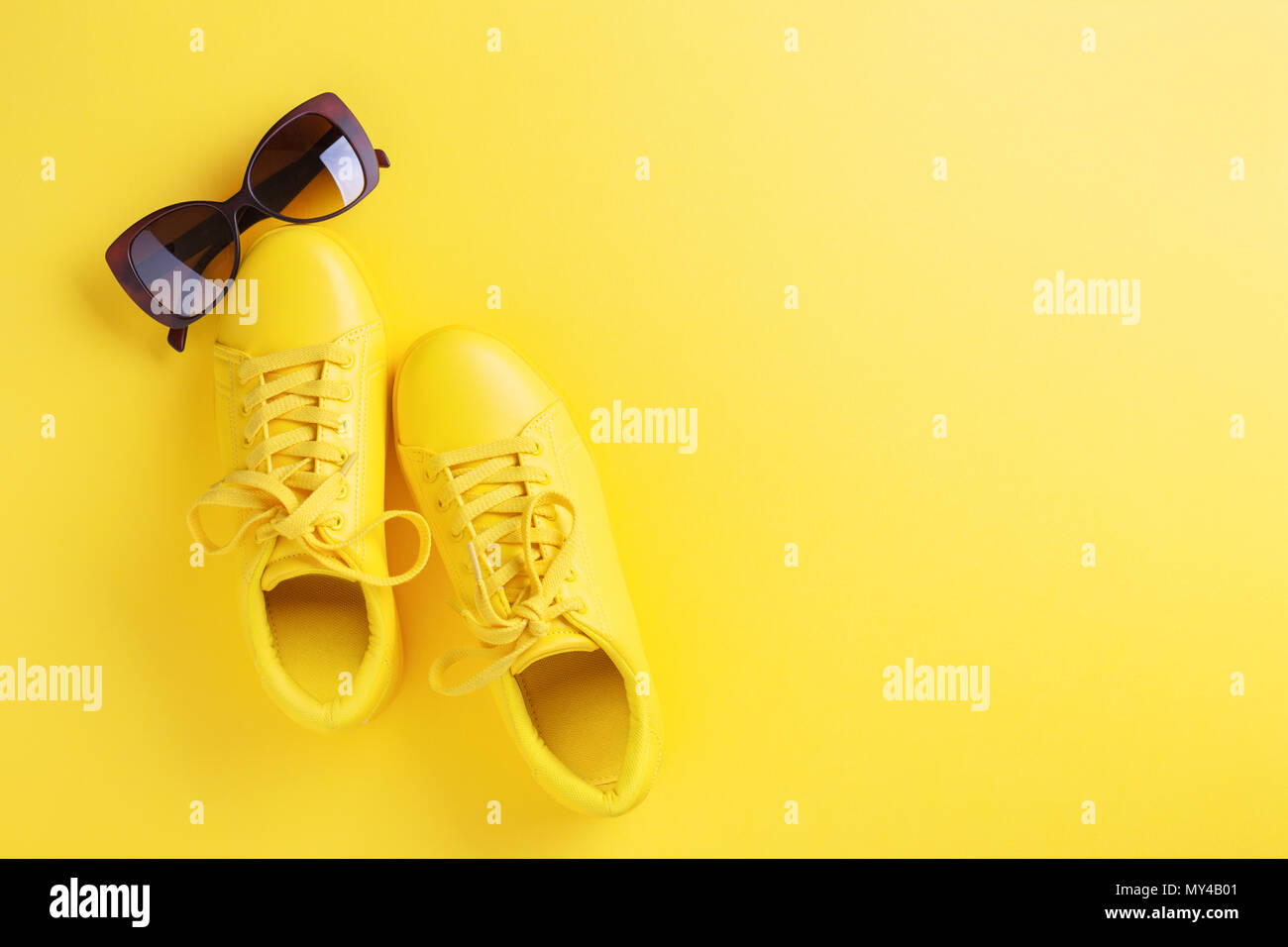 Pair of yellow shoes on yellow background with sunglasses. Trendy ...