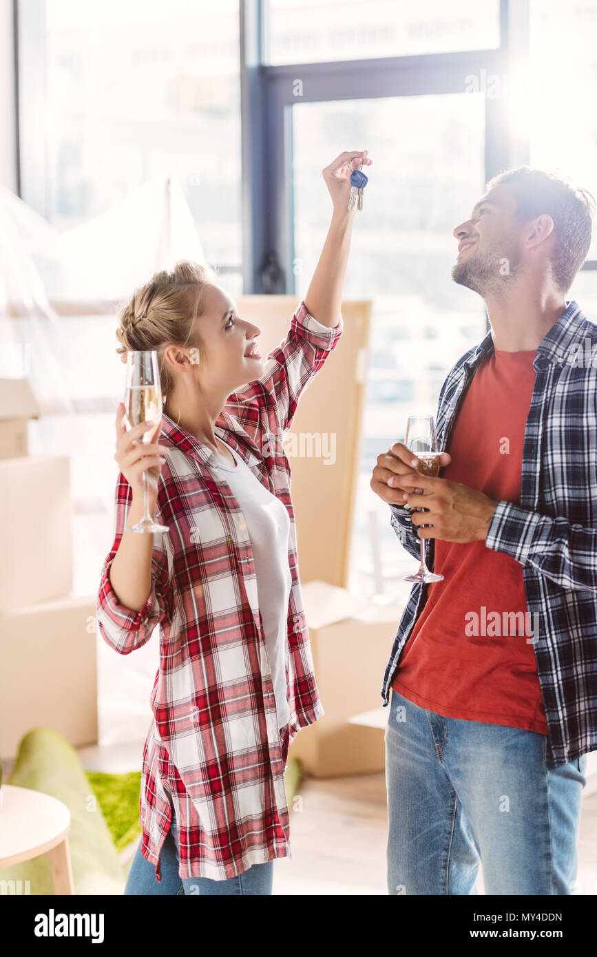 happy young couple drinking champagne and looking at keys from new ...