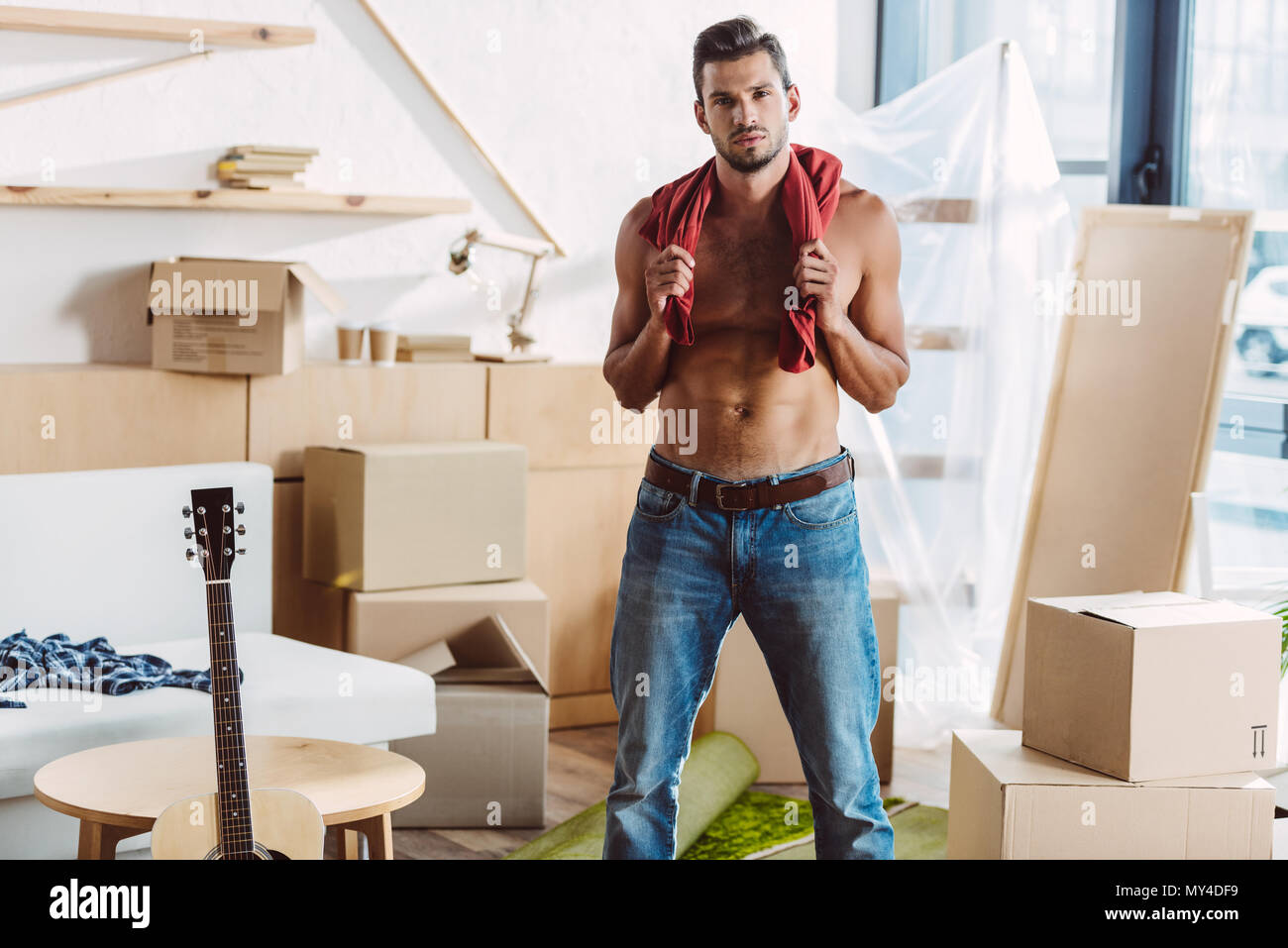 handsome shirtless man with t-shirt on shoulders standing and looking ...