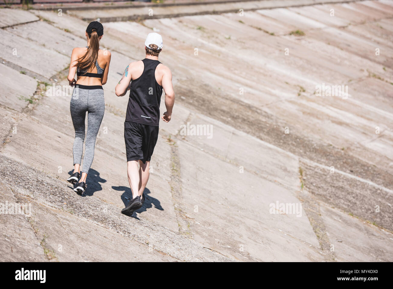 back view of athletic couple jogging together on slabs Stock Photo - Alamy