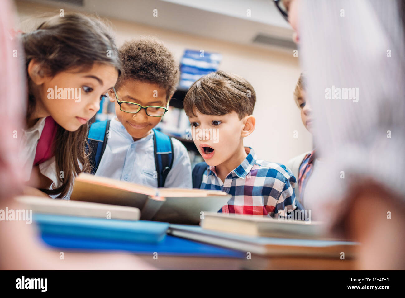shocked little children looking at book in library Stock Photo - Alamy