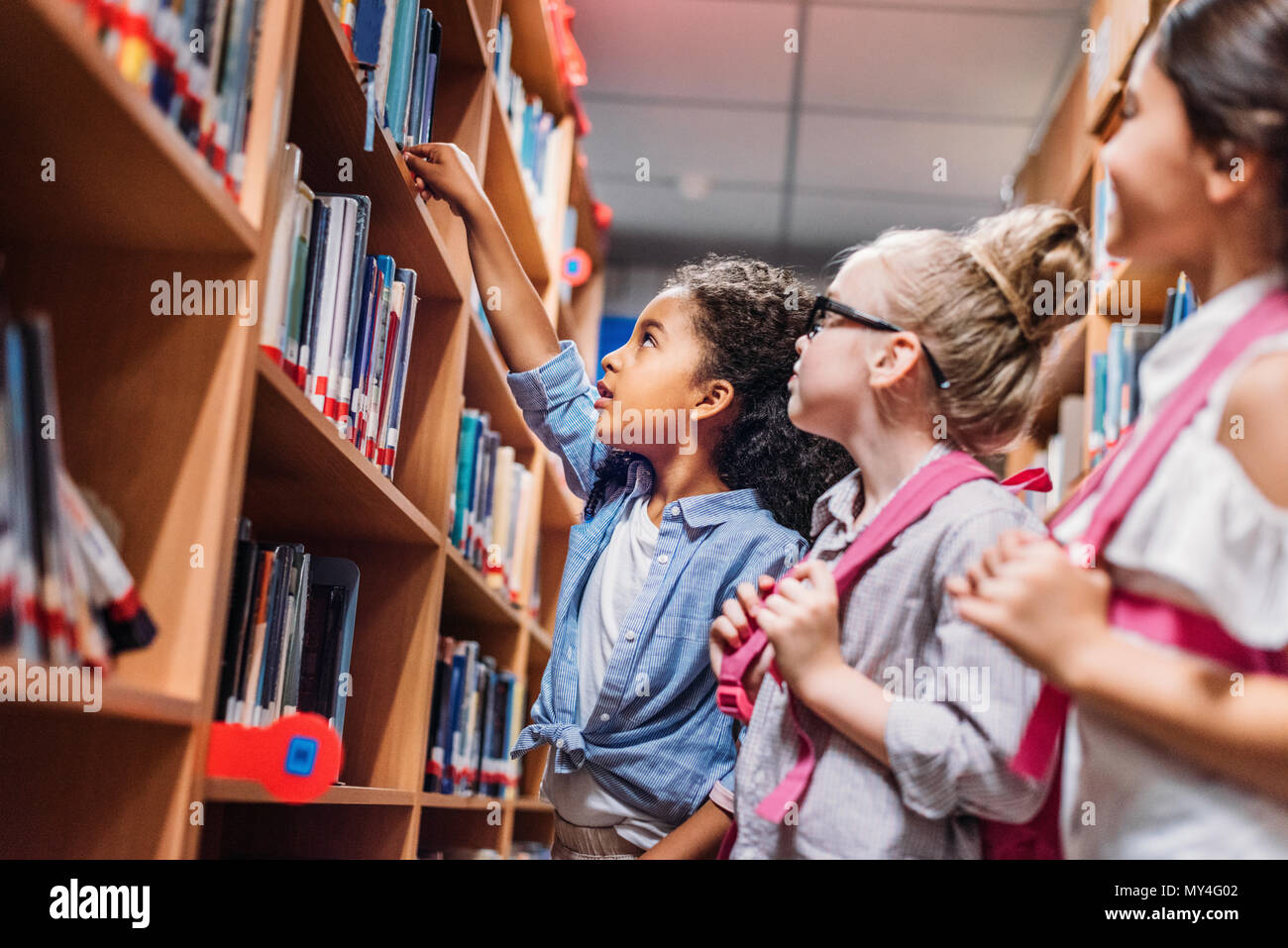 beautiful little schoolgirls looking for books in library Stock Photo ...
