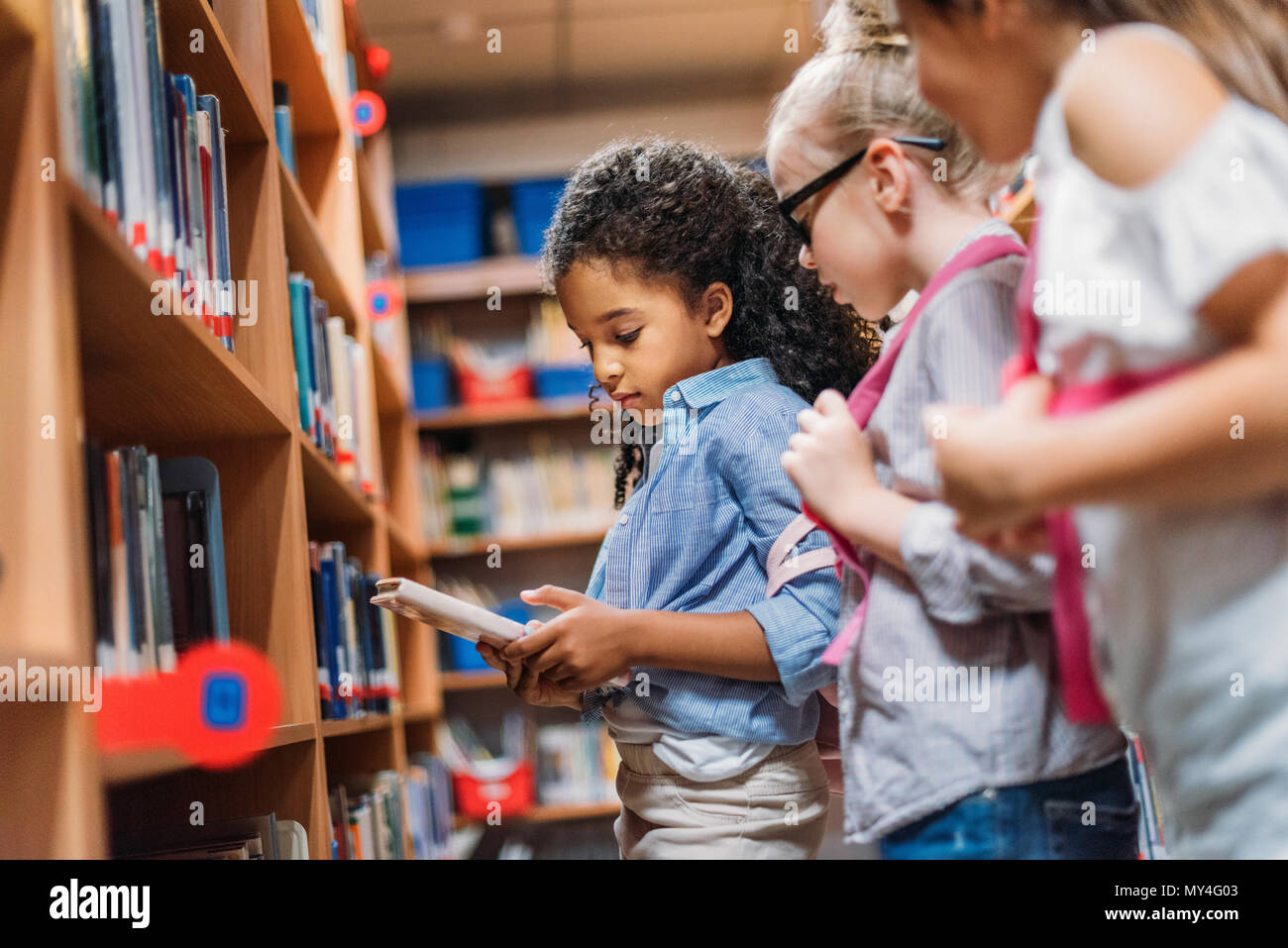 beautiful little schoolgirls looking for books in library Stock Photo ...