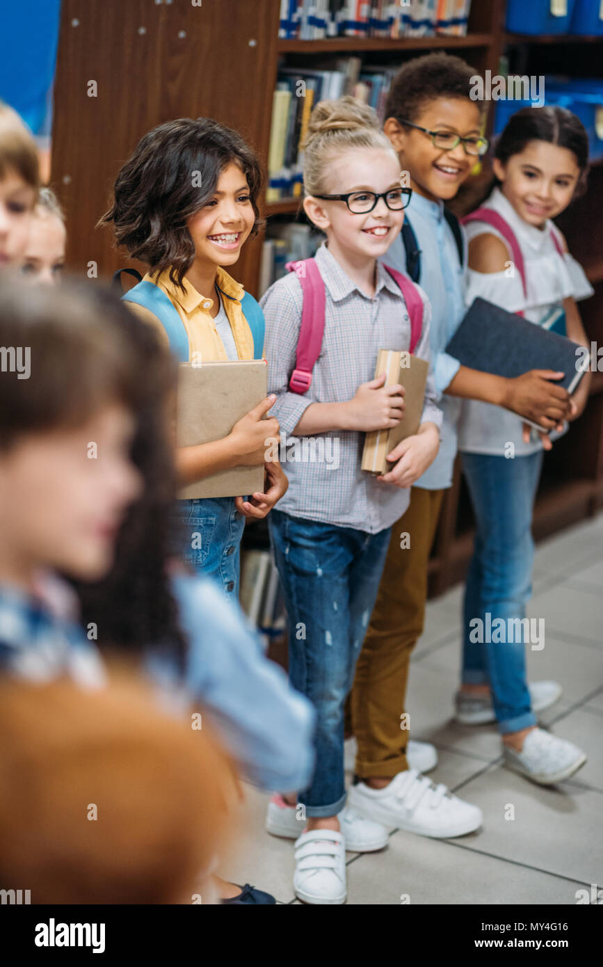 cute kids in library standing in row with books Stock Photo - Alamy